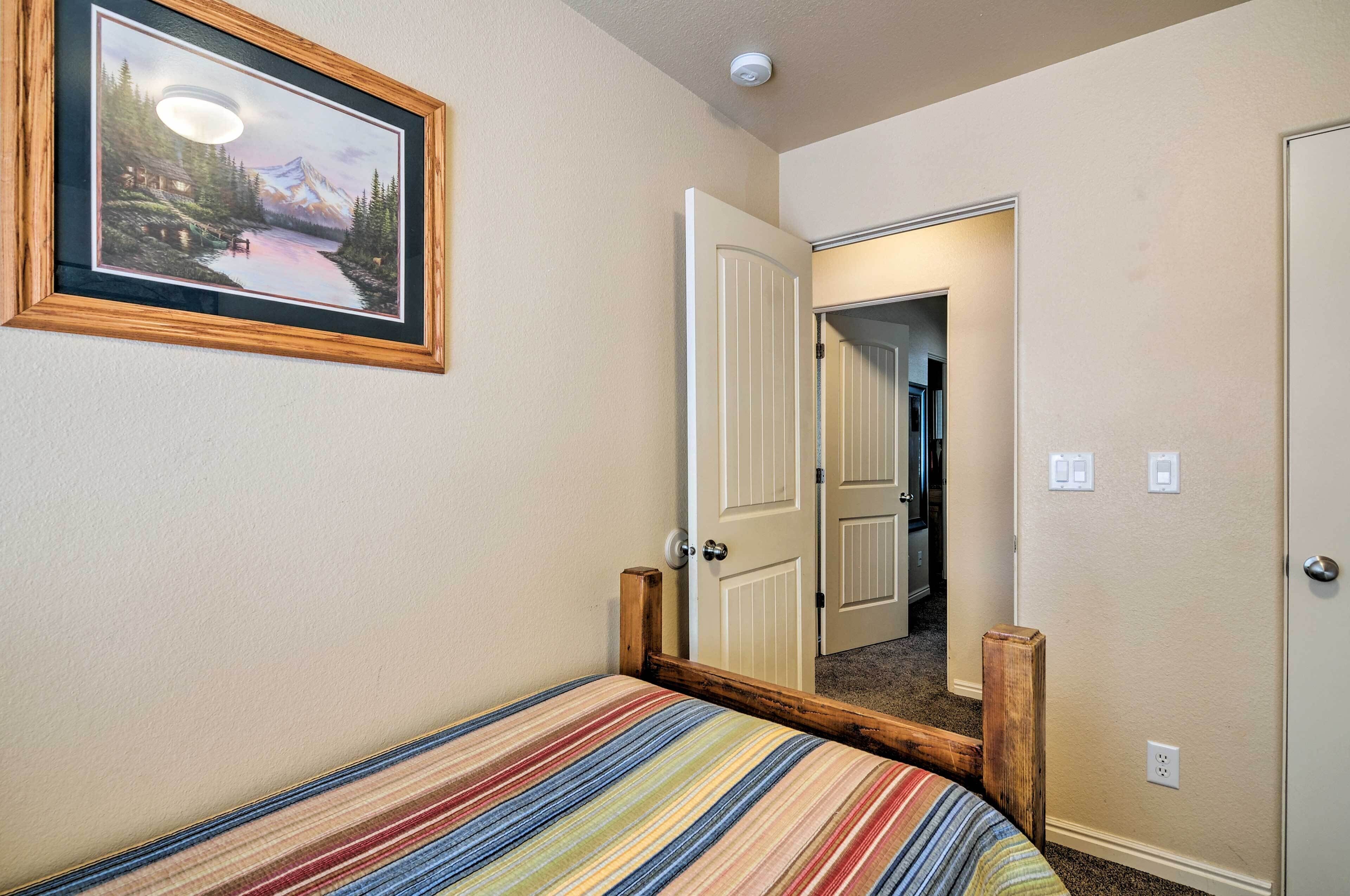 Quarto com uma cama, um quadro na parede e uma porta que dá para outro cômodo.