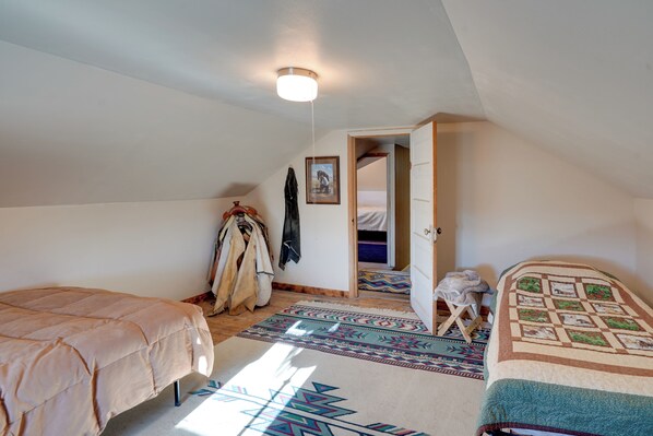 Quarto com cama, guarda-roupa, cabideiro e porta para outro espaço.