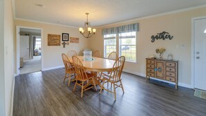 Uma sala de jantar com mesa e cadeiras de madeira, um candelabro e um armário com objetos decorativos.