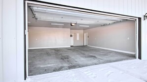 Uma garagem com piso de concreto e porta entreaberta.