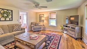 Sala de estar com sofá, mesa de centro, rack para TV e ventilador de teto.