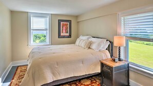 Um quarto com uma cama grande, uma mesa de cabeceira, uma luminária e uma janela com persianas.