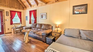 Um quarto acolhedor com teto de madeira, um sofá, uma cama, uma mesa e um abajur.
