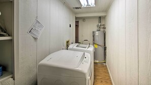 Um corredor estreito com dois eletrodomésticos brancos, um aquecedor de água e um papel fixado na parede.