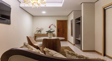 Uma sala de estar moderna com um sofá, uma mesa de centro e um espaço de jantar com cadeiras e um vaso de flores.