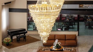 Um hall amplo com um lustre imponente, sofás de couro e um piano.