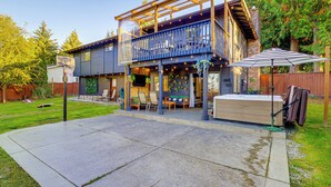 Uma casa de dois andares com varanda, cesta de basquete e um pátio com mobiliário de exterior.