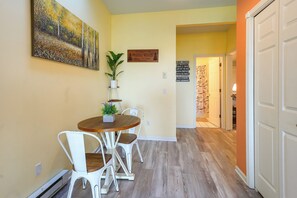 Uma área de refeições com mesa, cadeiras, um vaso de planta e uma placa de boas-vindas.