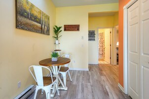 Uma área de refeições com mesa, cadeiras, um vaso de planta e uma placa de boas-vindas.