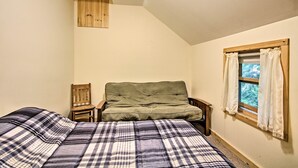 Quarto com cama, poltrona, janela com cortinas e painel de madeira na parede.