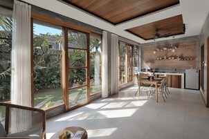 Cozinha espaçosa com grandes janelas, espaço de refeições e vista para um jardim.