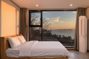 Quarto com uma janela grande, uma cama e aparelho de ar condicionado.