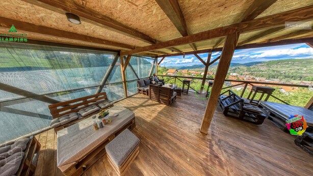 Um deck de madeira com mesa e bancos, com vista para uma paisagem deslumbrante.