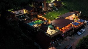 Resort com várias cabanas de madeira, piscina e áreas de estar ao ar livre.