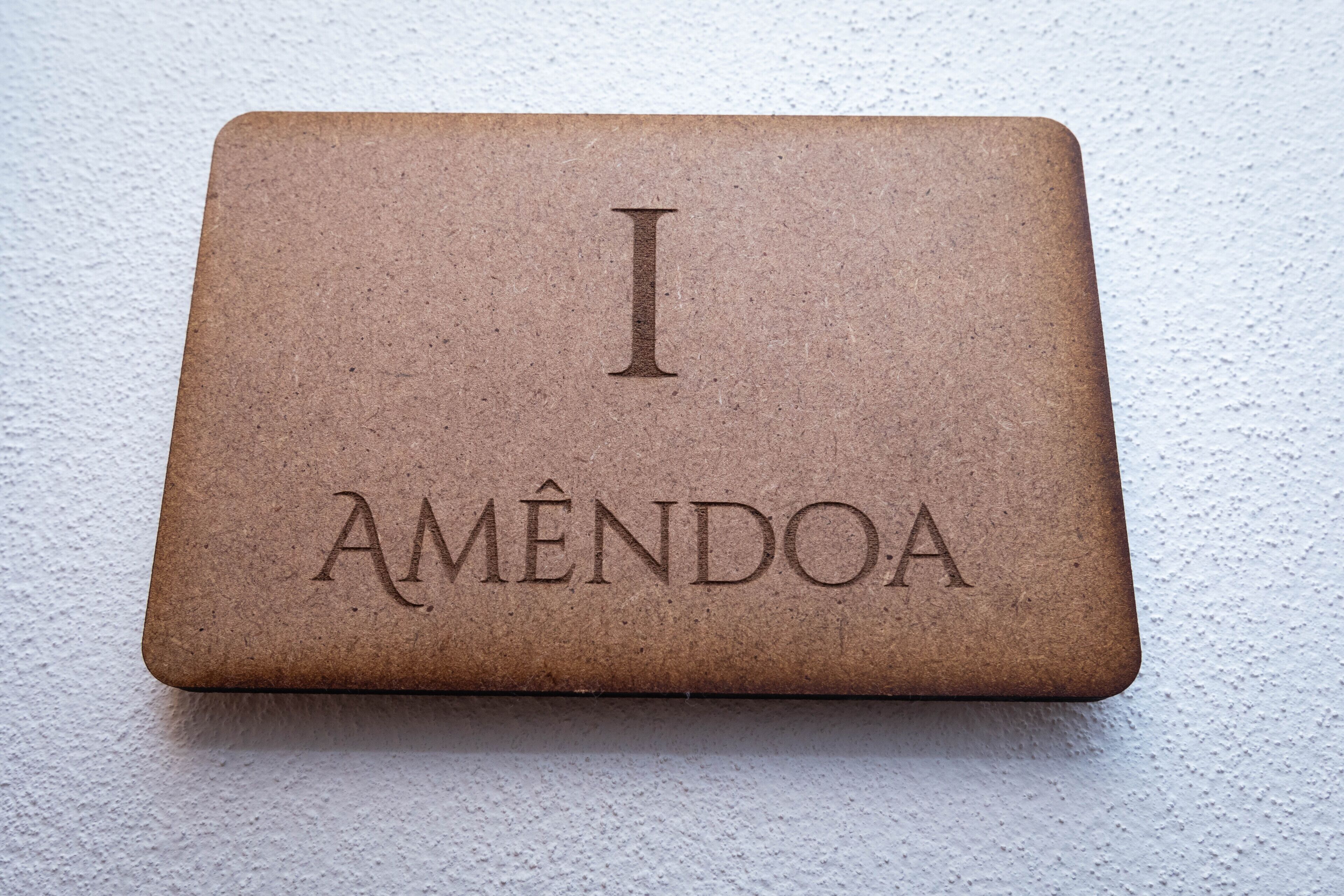 Um objeto retangular com texto em relevo que diz 'I AMÊDOA'.