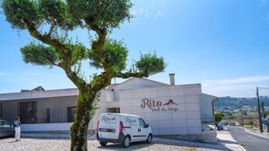 Uma carrinha branca estacionada em frente a um edifício com uma placa que diz 'Rito Hall da Serra'.