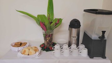 Uma estação de café com cafeteira, xícaras e uma planta.