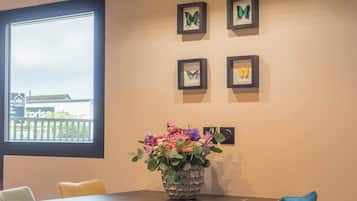 Uma sala de jantar com uma mesa de madeira, duas cadeiras, um vaso com flores e arte de parede com borboletas.