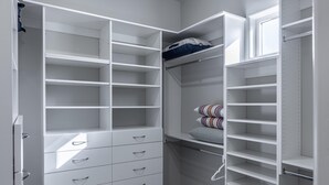 Um closet amplo com prateleiras abertas, gavetas e espaço para pendurar roupas.