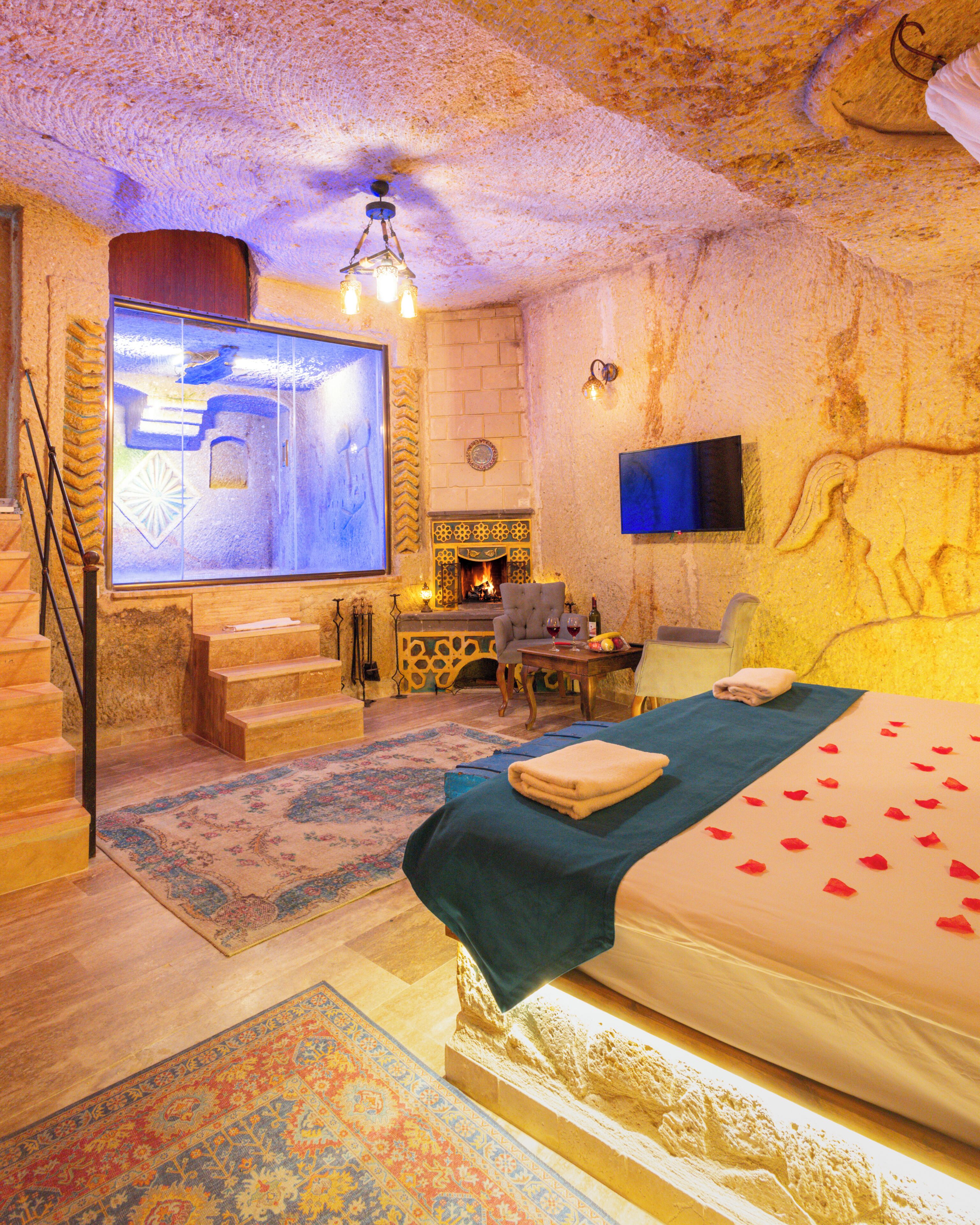 Um quarto com cama, lareira, televisão e escada.