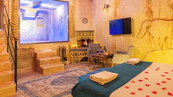 Um quarto com cama, lareira, televisão e escada.