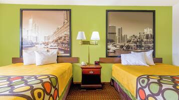 Quarto de hotel com duas camas, paredes verdes e cartazes com vistas da cidade.