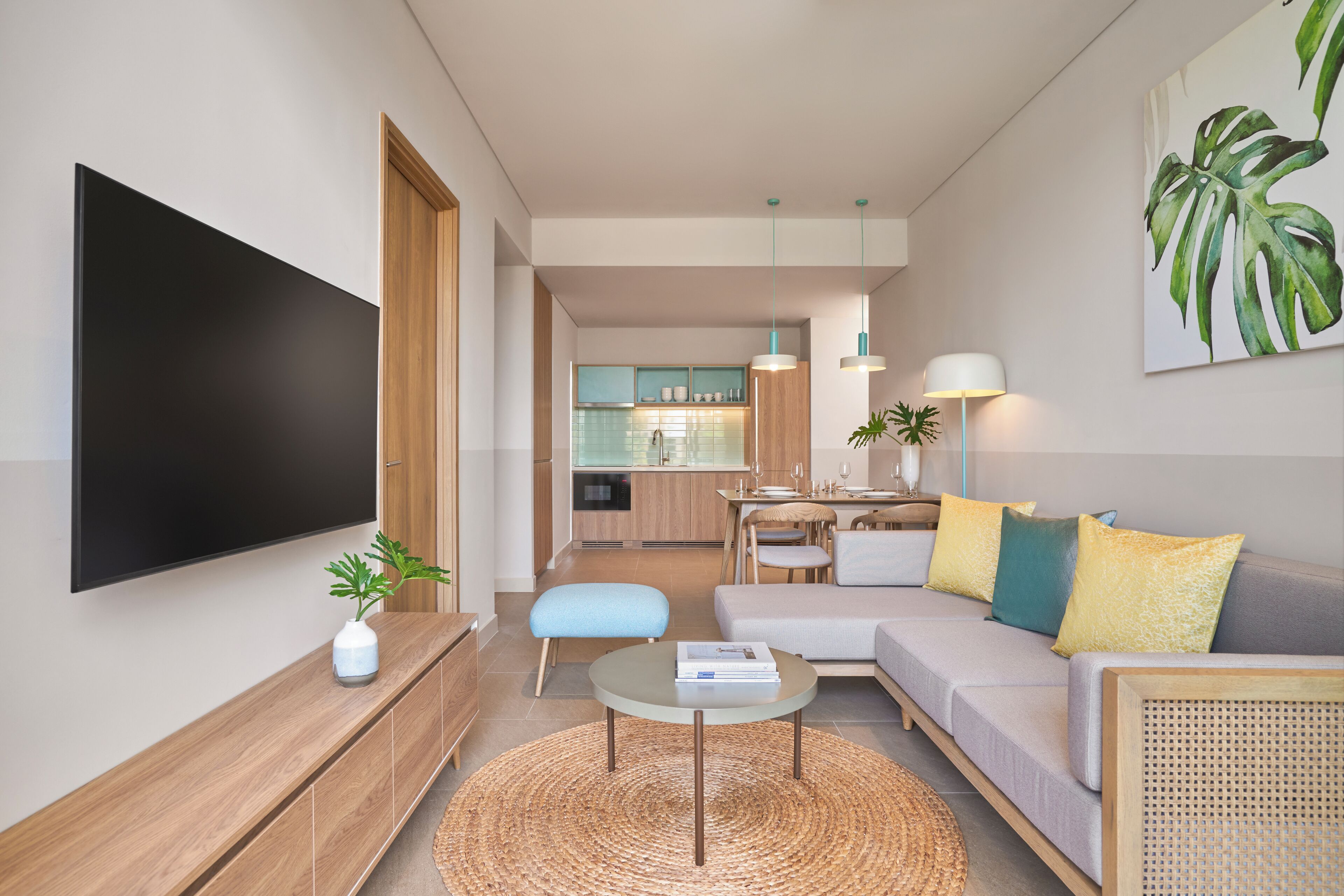 Uma sala de estar moderna com televisão de tela plana, sofá, mesa de centro e uma área de refeições ao fundo.