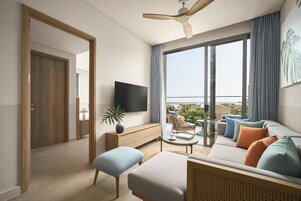 Uma sala de estar moderna com televisão de tela plana, um sofá com almofadas, uma mesa de centro e um ventilador de teto.