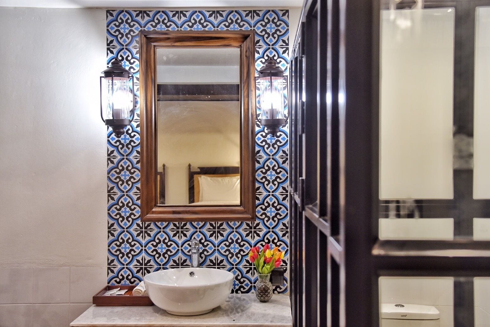 Casa de banho com um espelho grande, lavatório e azulejos decorativos.