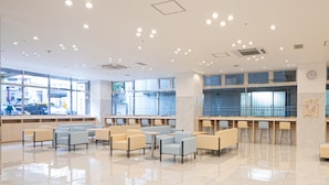 Amplo espaço interno, bem iluminado, com diversas opções de assentos e grandes janelas que proporcionam luz natural.