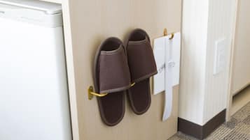 Um par de chinelos marrons pendurados em um suporte de metal fixado em uma porta de madeira.