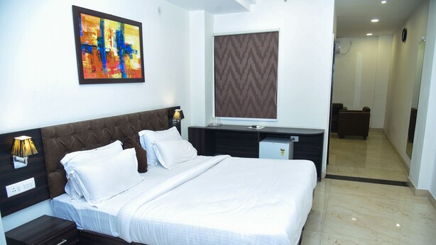 Cama bem arrumada com roupa de cama branca, cabeceira escura e mesa de cabeceira com abajur.