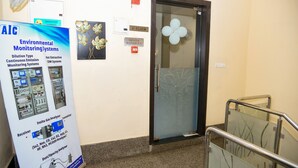 Um corredor com porta de vidro, placa indicando o 4º andar e um cartaz para os Sistemas de Monitoramento Ambiental AIC.