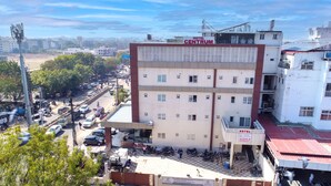 Edifício de hotel com vários andares, área de estacionamento coberta e placa indicando quartos de hotel e salão de festas.