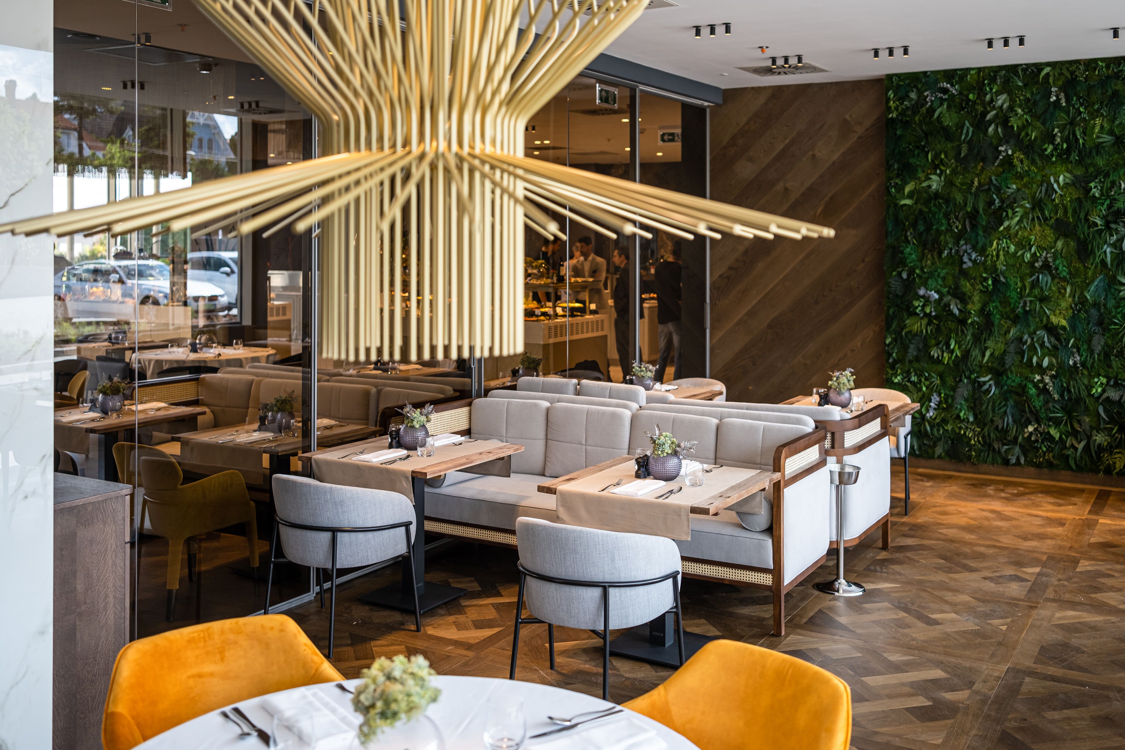 Um restaurante moderno com área de estar central, piso de madeira e parede verde.