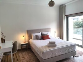 Quarto moderno com cama grande, mesas de cabeceira, escrivaninha e uma cadeira.