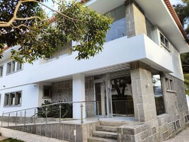 Um edifício moderno de dois andares com fachada branca, grandes janelas e base de pedra.