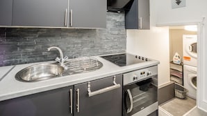Cozinha moderna com armários cinzas, pia de aço inoxidável, forno embutido e lava-louças.