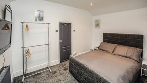 Quarto com cama, guarda-roupa, porta e radiador.