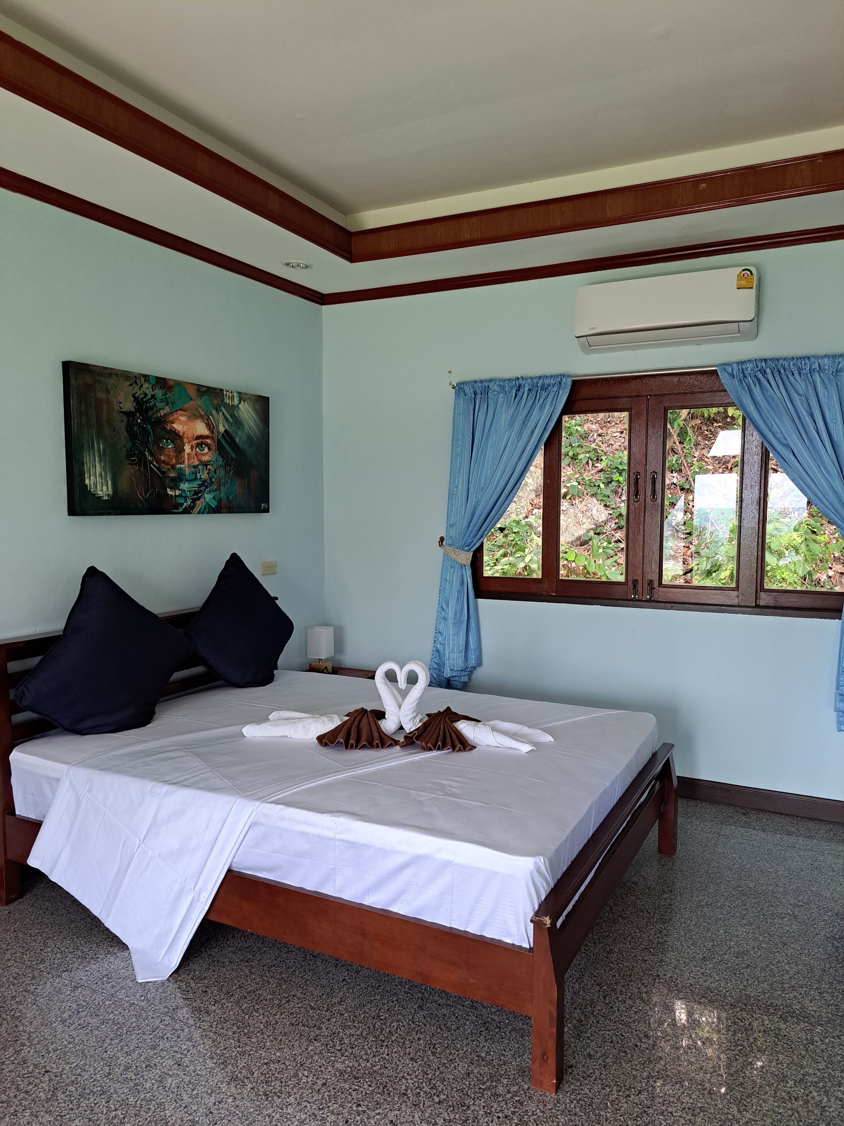 Quarto de hotel com cama, um quadro na parede e janela com cortinas.