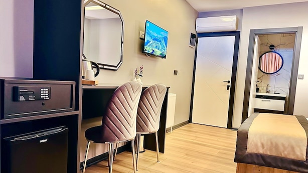 Quarto de hotel com cama, escrivaninha, computador, cadeira, televisão e minibar.
