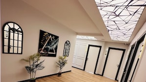 Quarto amplo com piso de madeira, claraboia e duas portas.