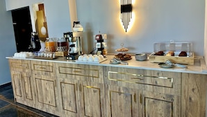 Balcão de café da manhã com máquinas de café, chá e doces.