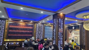 Restaurante com interior moderno, apresentando paredes com padrão e um candelabro.
