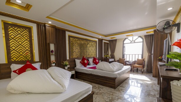 Quarto de hotel com duas camas, um espaço de estar e uma janela grande.