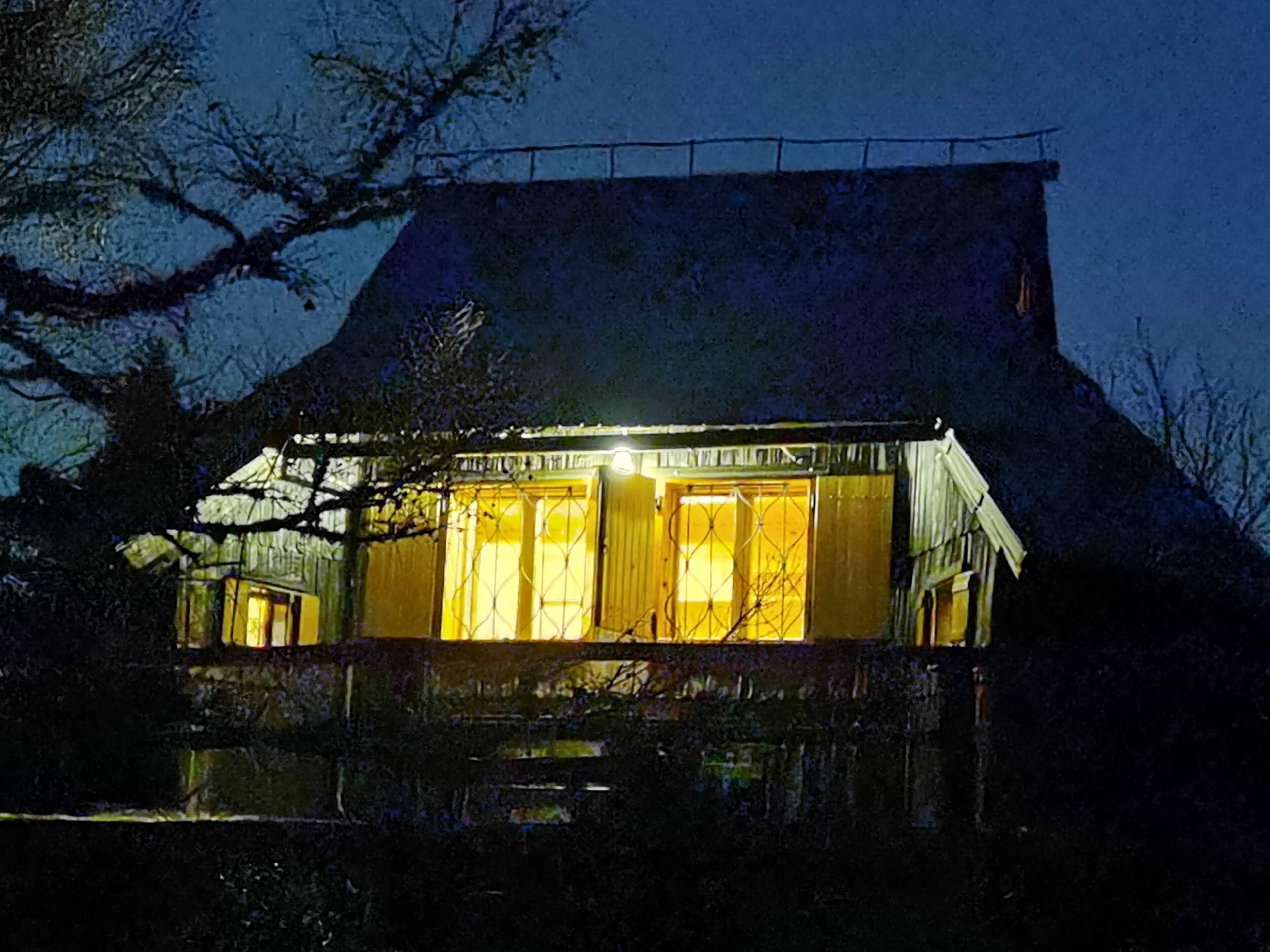 Uma casa com um telhado grande e inclinado e um jardim frontal cercado.