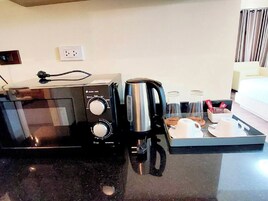 Uma cozinha compacta equipada com micro-ondas, cafeteira e um suporte com xícaras e caixa de lenços.