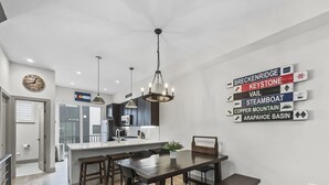 Cozinha moderna com ilha central, iluminação pendente e um letreiro na parede com símbolos de direção.
