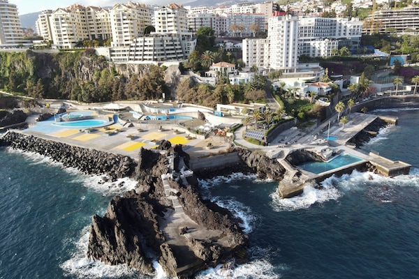 Perto da praia, areia preta, espreguiçadeiras, guarda-sóis