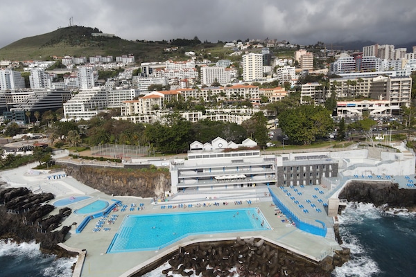 Perto da praia, areia preta, espreguiçadeiras, guarda-sóis